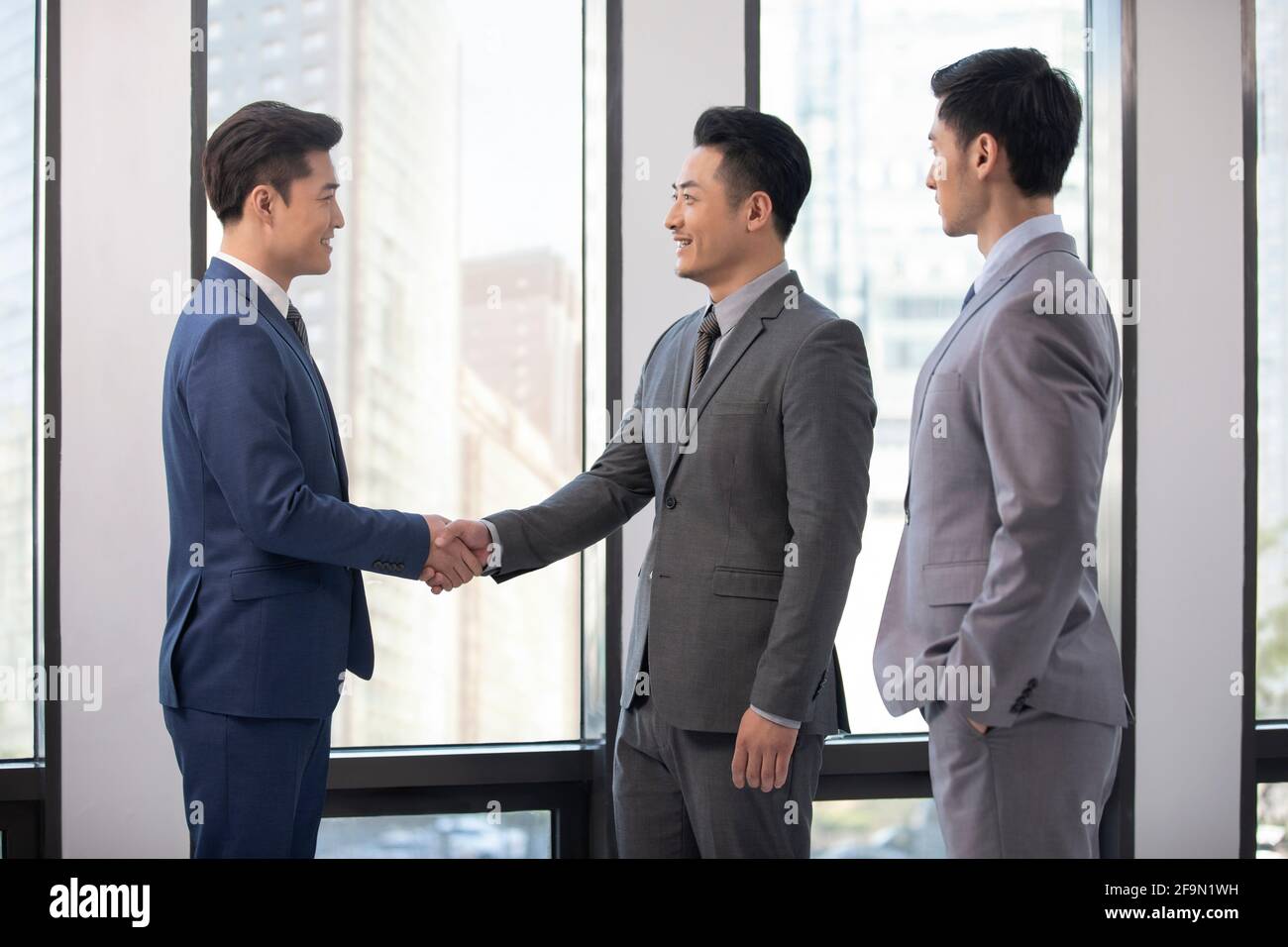 Standing shaking hands looking away smiling greeting hi-res stock ...