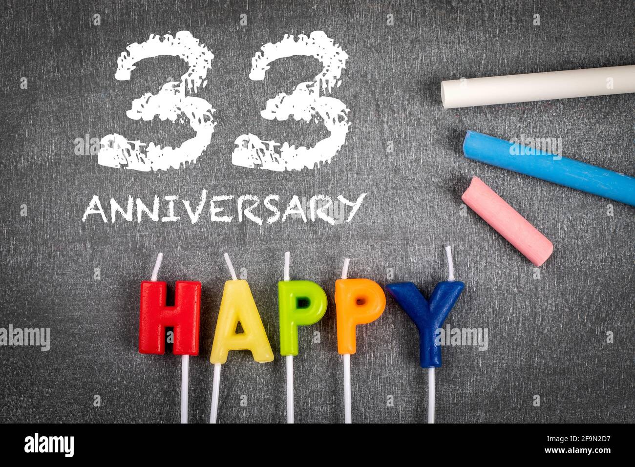 33 year anniversary. Candles and colored crayons on a dark chalk board ...