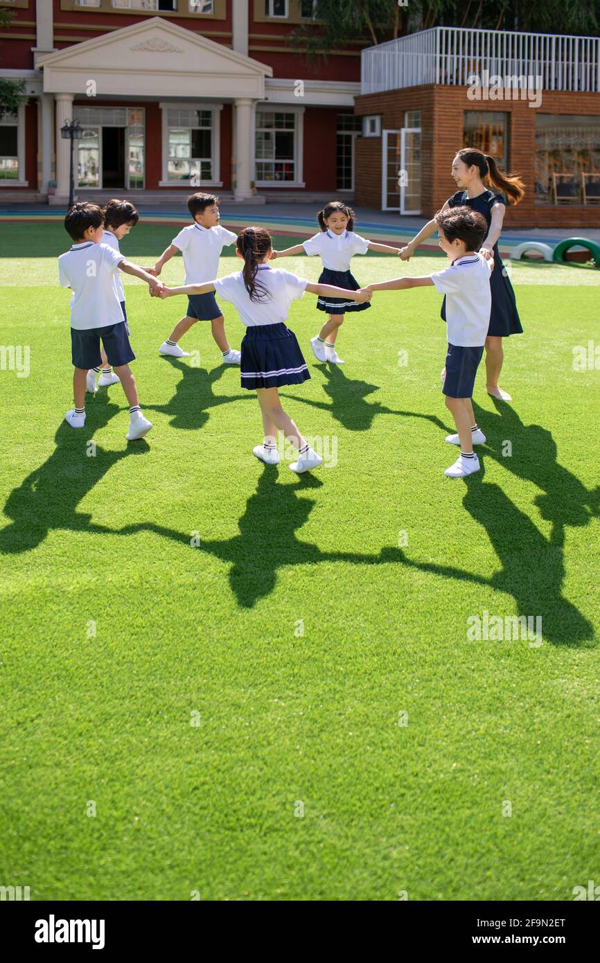 Teacher and students playing in kindergarten playground Stock Photo - Alamy