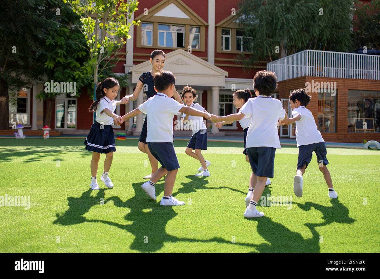 Teacher and students playing in kindergarten playground Stock Photo - Alamy