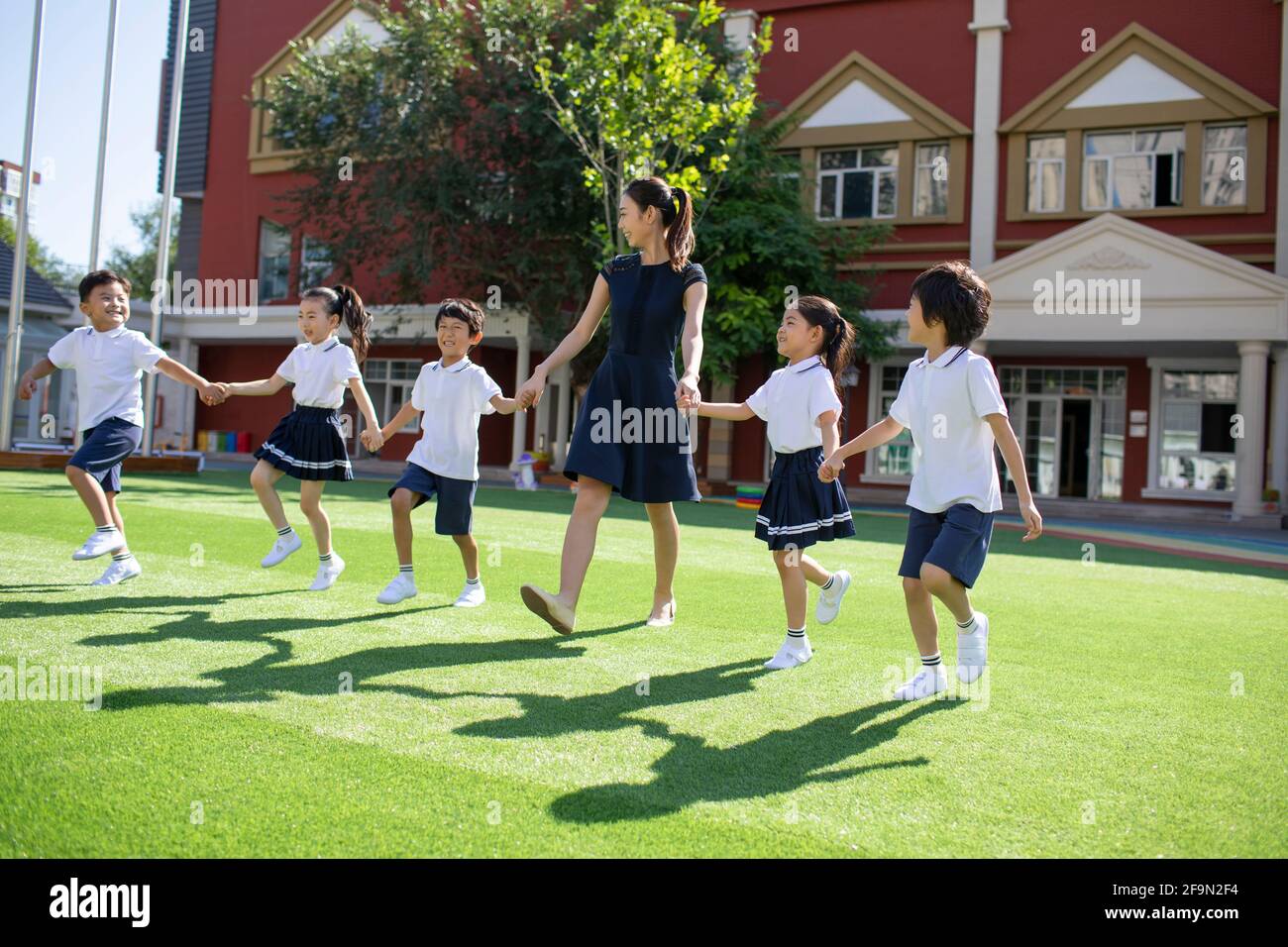 Teacher and students in kindergarten playground Stock Photo - Alamy