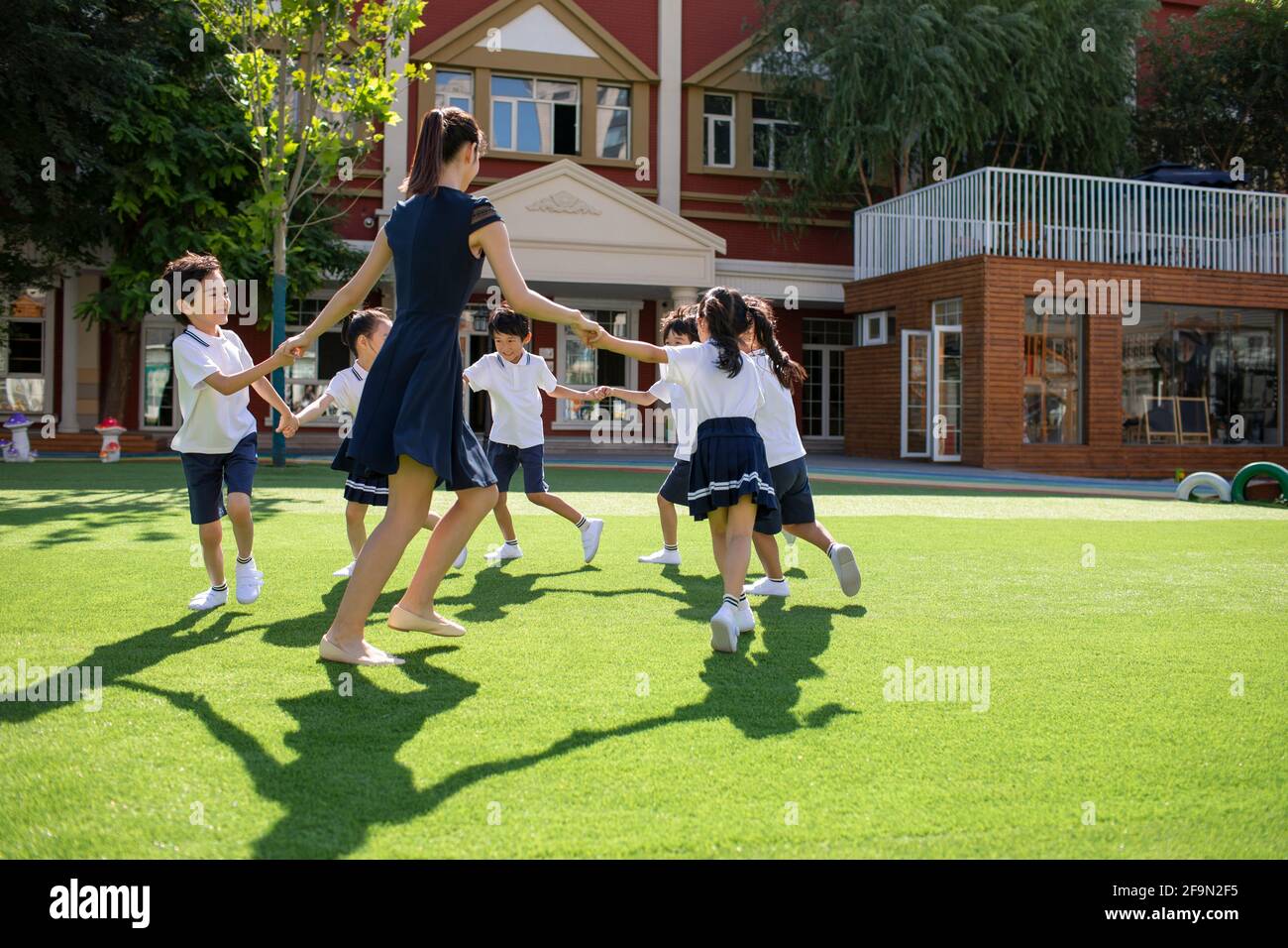 Teacher and students playing in kindergarten playground Stock Photo - Alamy