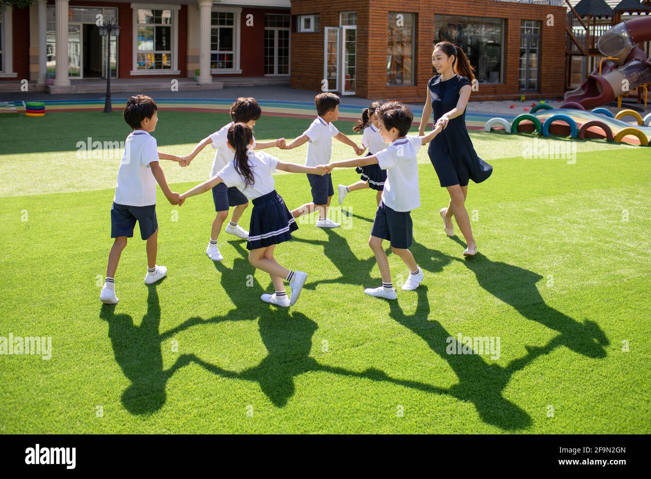 Teacher and students playing in kindergarten playground Stock Photo - Alamy