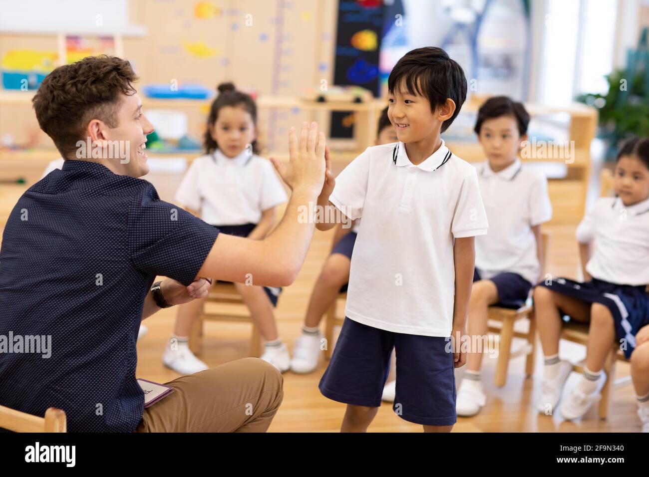 Foreign teacher teaching children English in classroom Stock Photo - Alamy