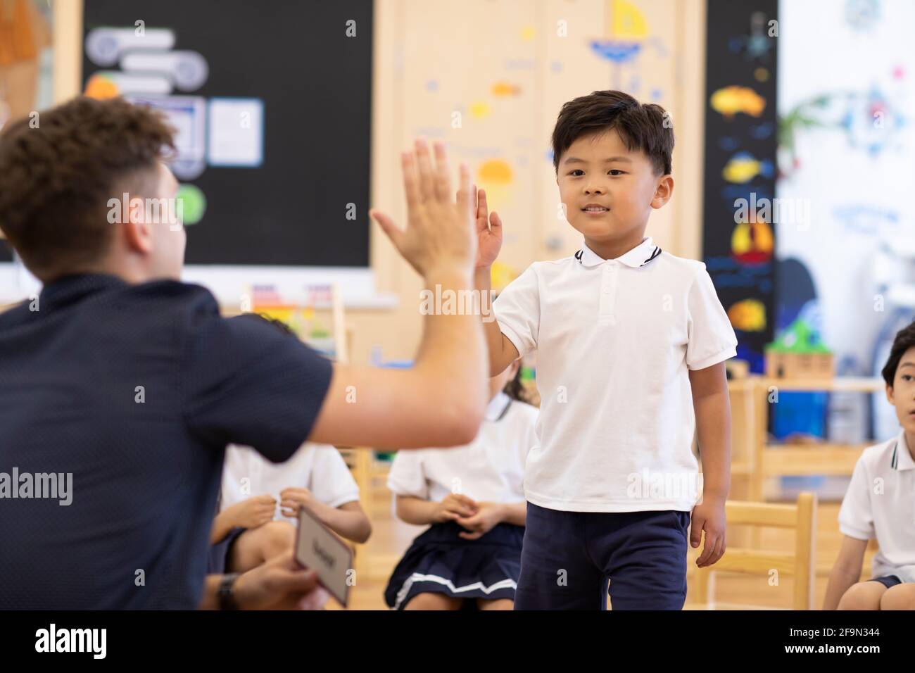 Foreign teacher teaching children English in classroom Stock Photo - Alamy