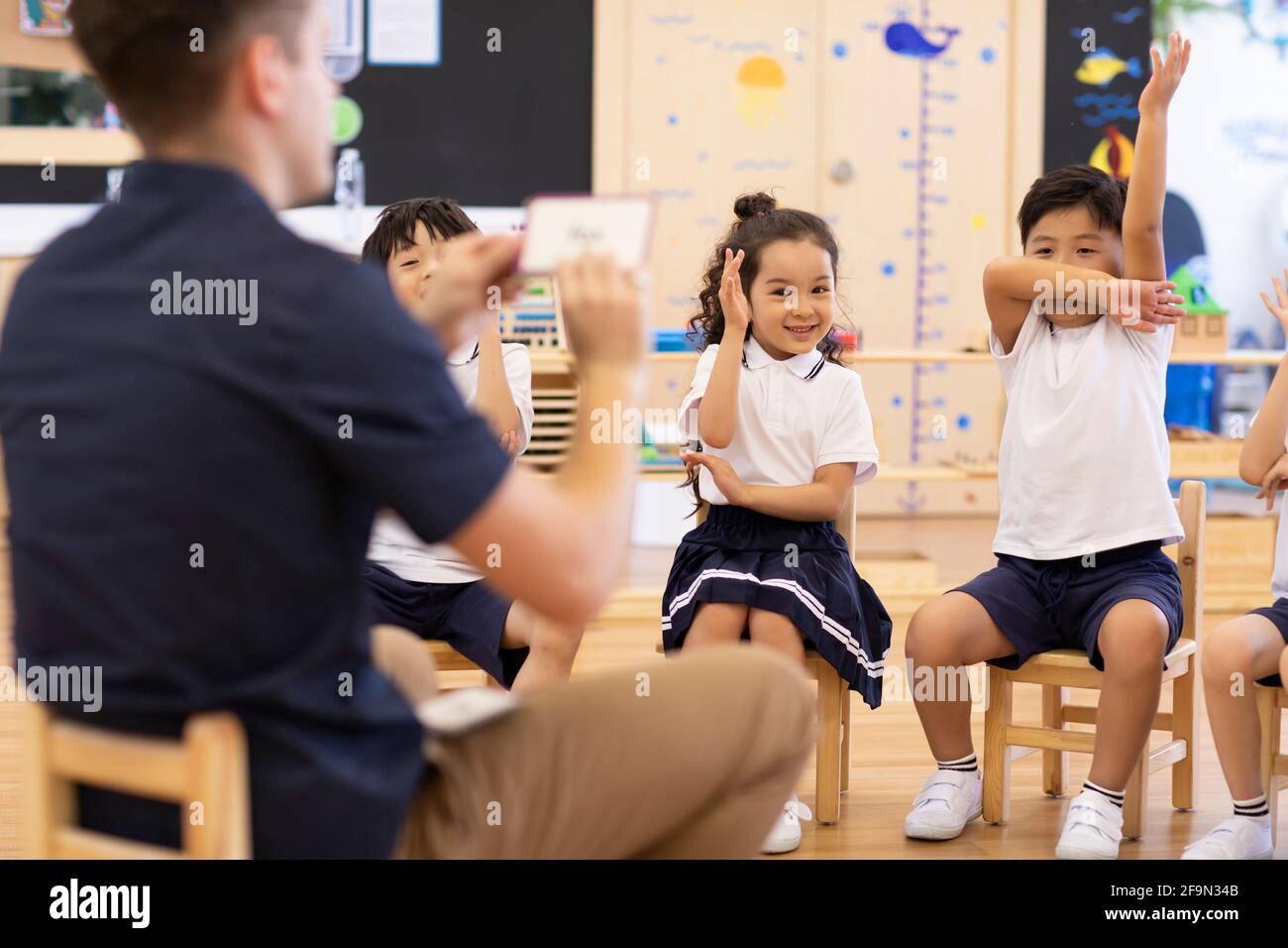 Foreign teacher teaching children English in classroom Stock Photo - Alamy