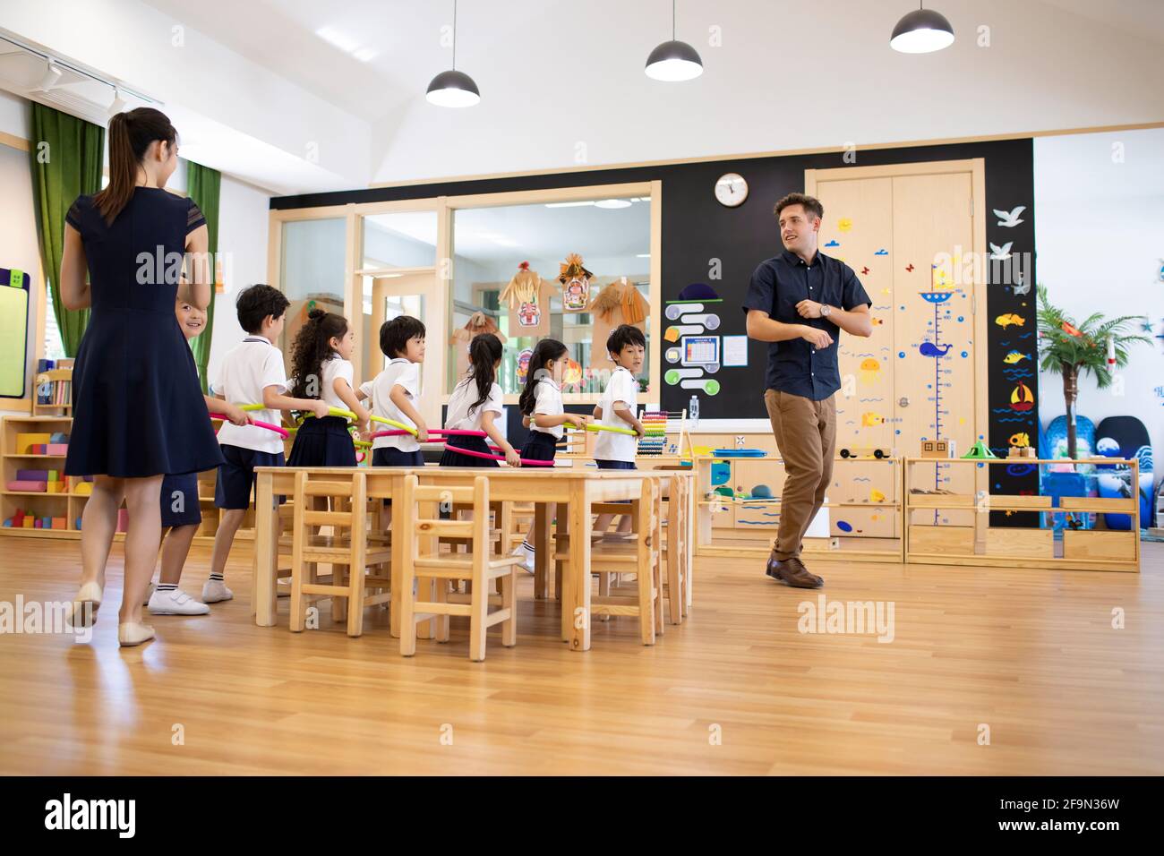 Teachers and children playing games in classroom Stock Photo - Alamy