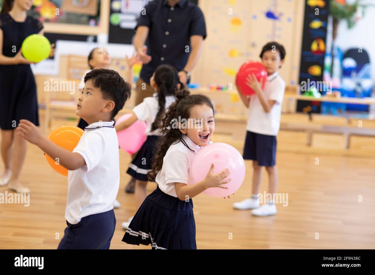 Teachers and children playing in classroom Stock Photo - Alamy