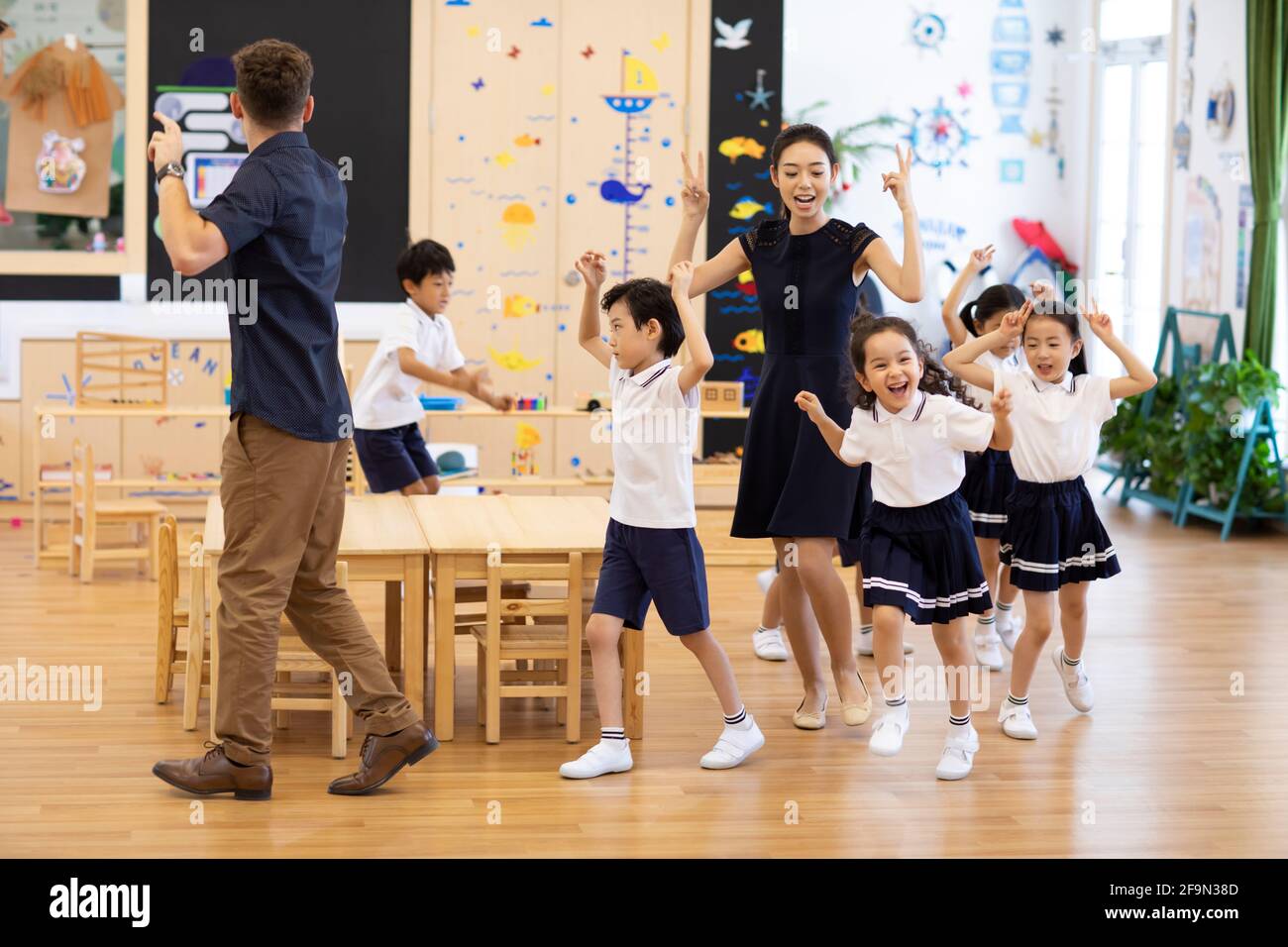 Teachers and children playing games in classroom Stock Photo - Alamy