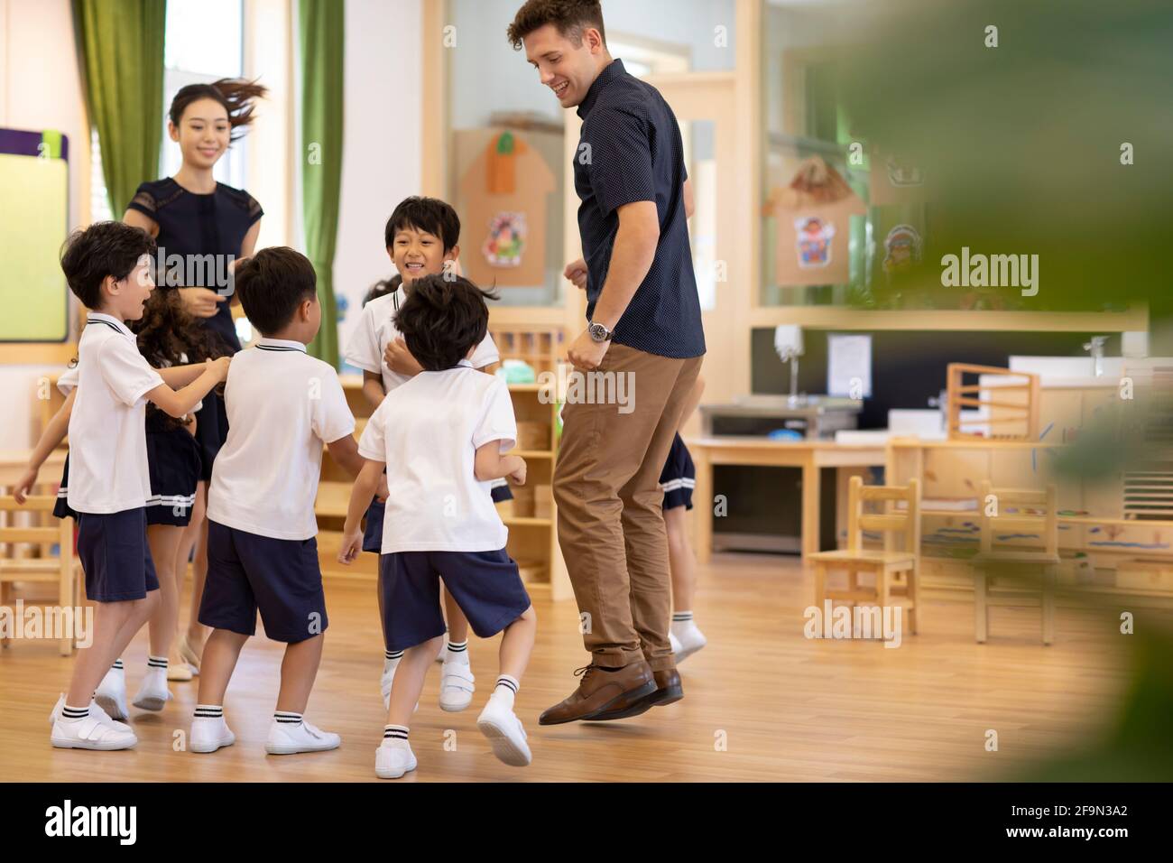 Teachers and children playing in classroom Stock Photo - Alamy