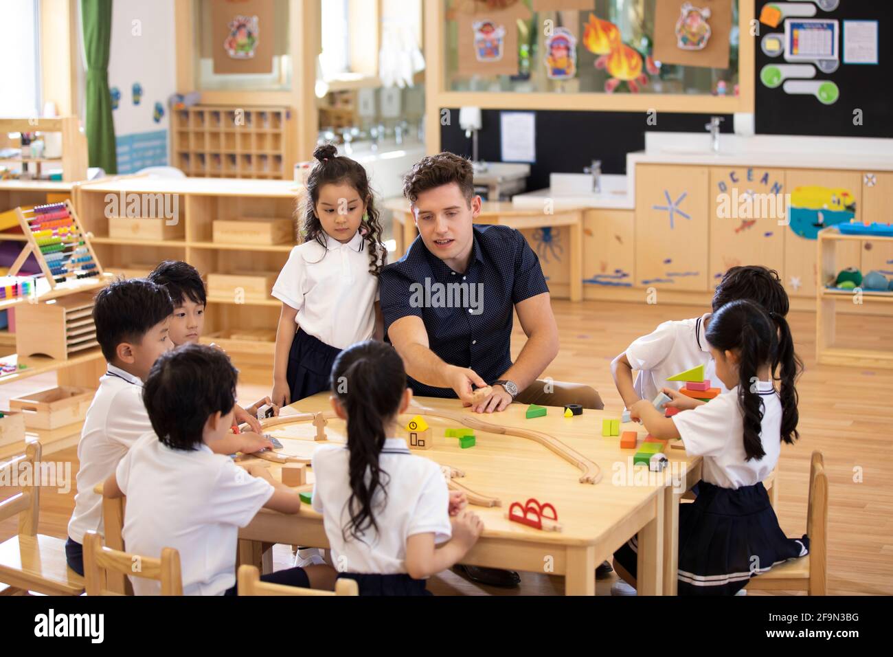 Foreign teacher and children playing in classroom Stock Photo - Alamy