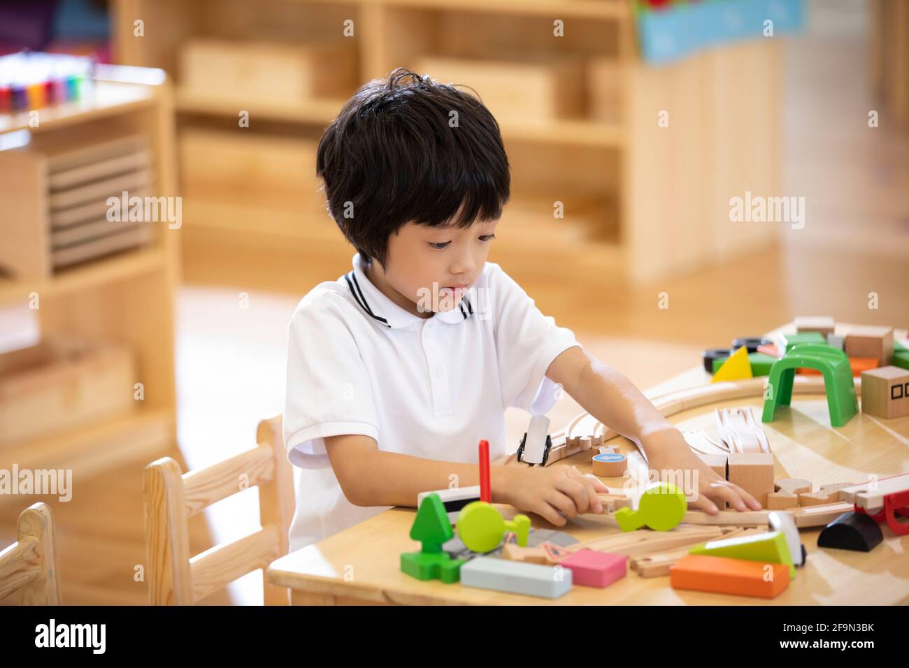 Little boy playing train set in classroom Stock Photo - Alamy