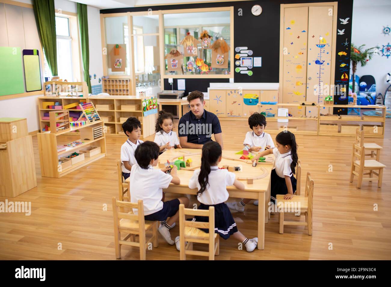 Foreign teacher and children playing in classroom Stock Photo - Alamy