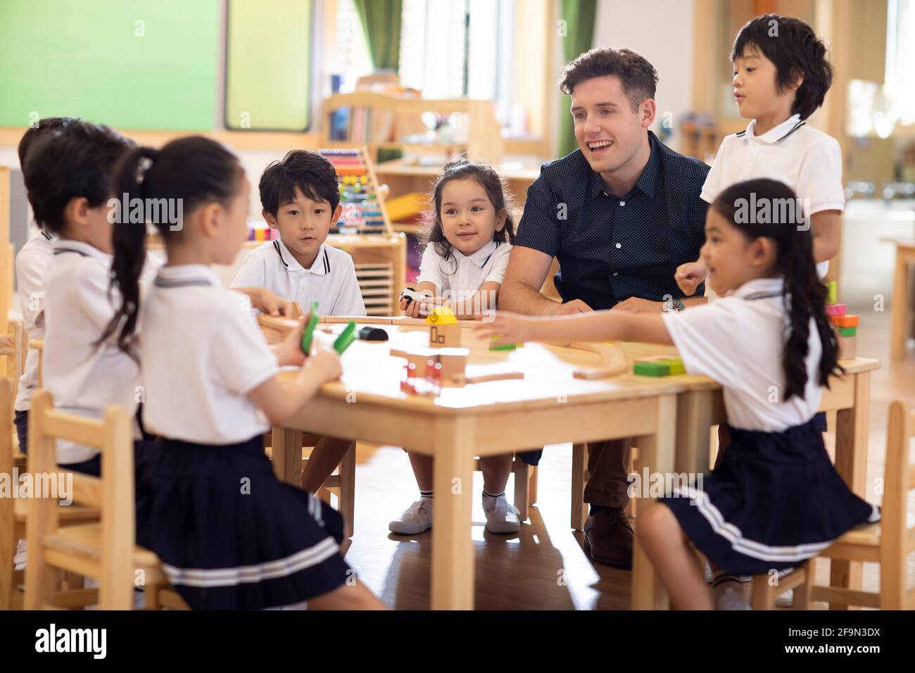 Foreign teacher and children playing in classroom Stock Photo - Alamy
