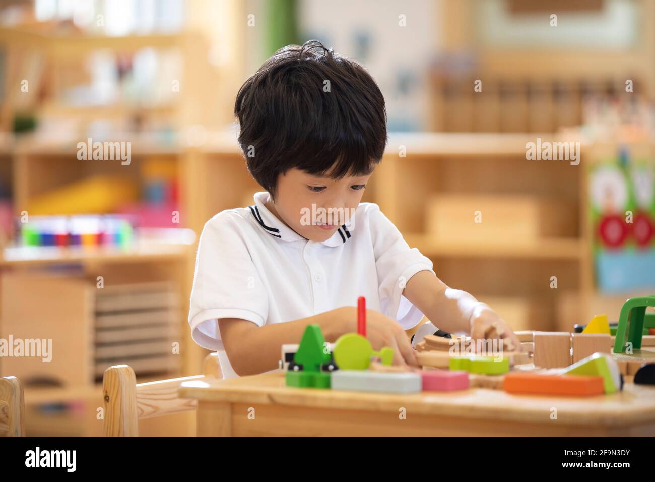 Little boy playing train set in classroom Stock Photo - Alamy
