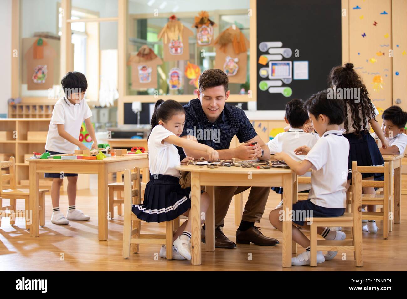 Foreign teacher and children playing in classroom Stock Photo - Alamy