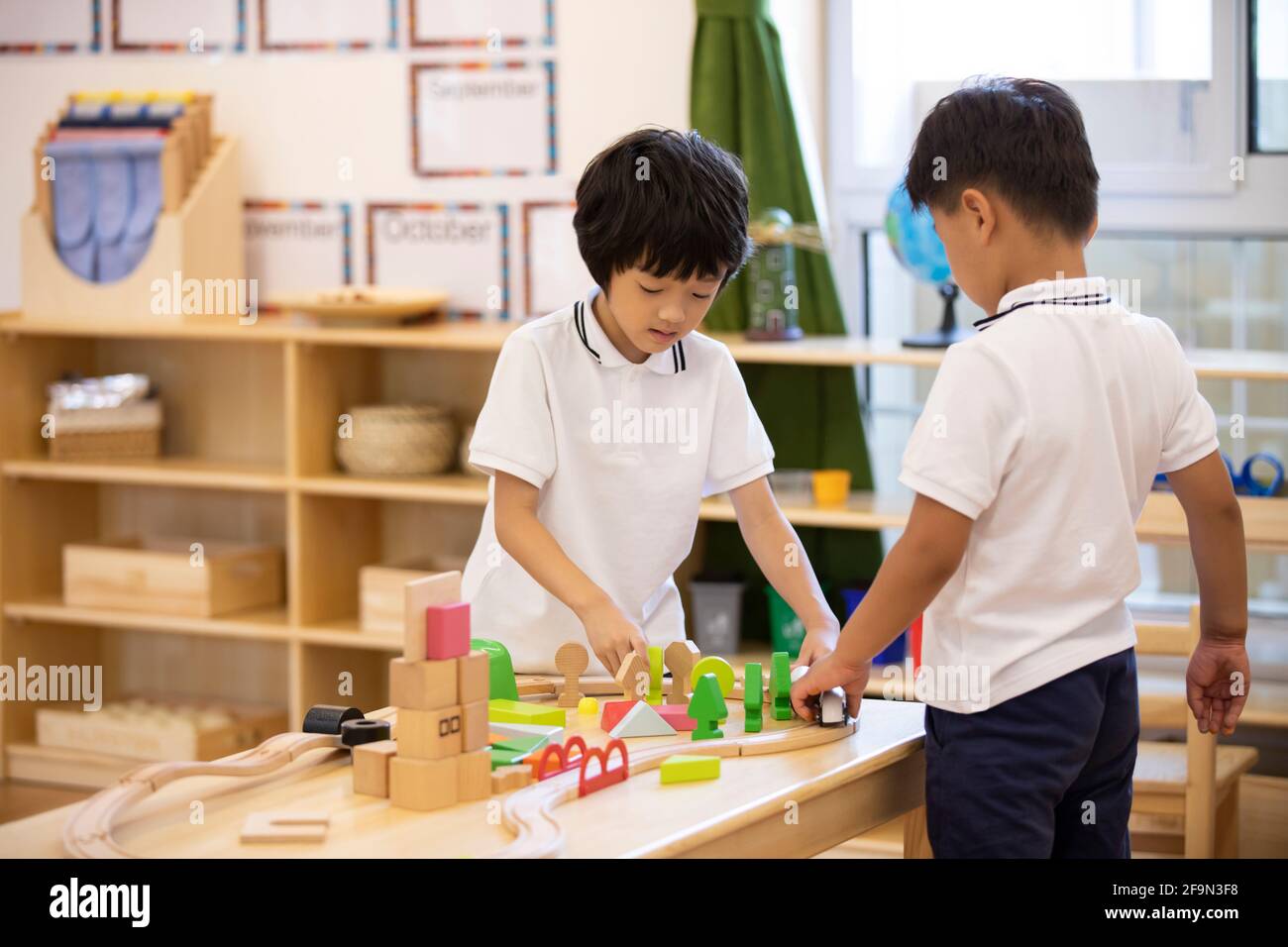 Little boys playing train set in classroom Stock Photo - Alamy