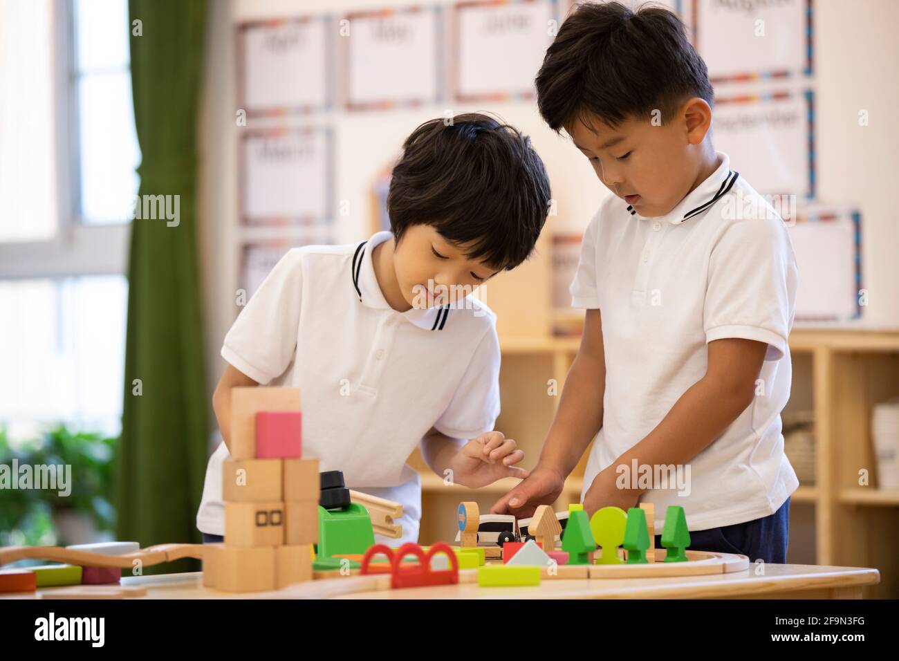 Little boys playing train set in classroom Stock Photo - Alamy