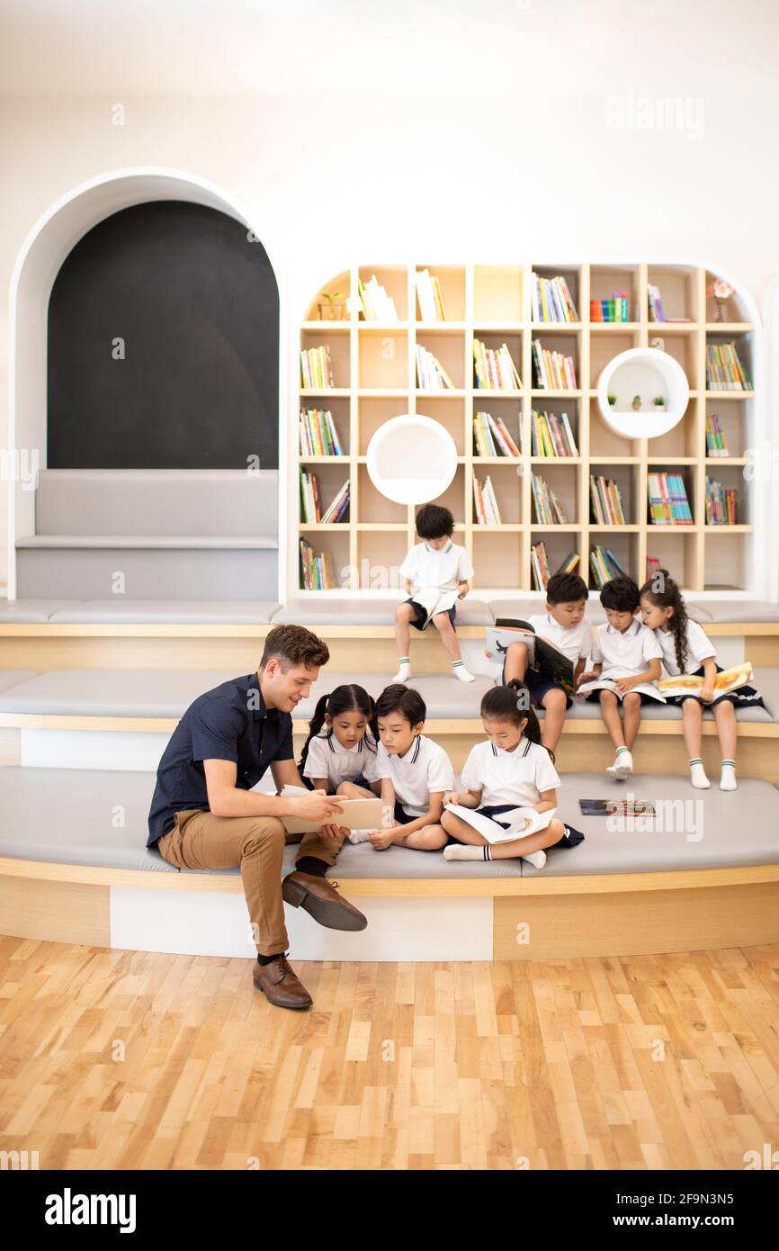 Children reading book in library Stock Photo - Alamy