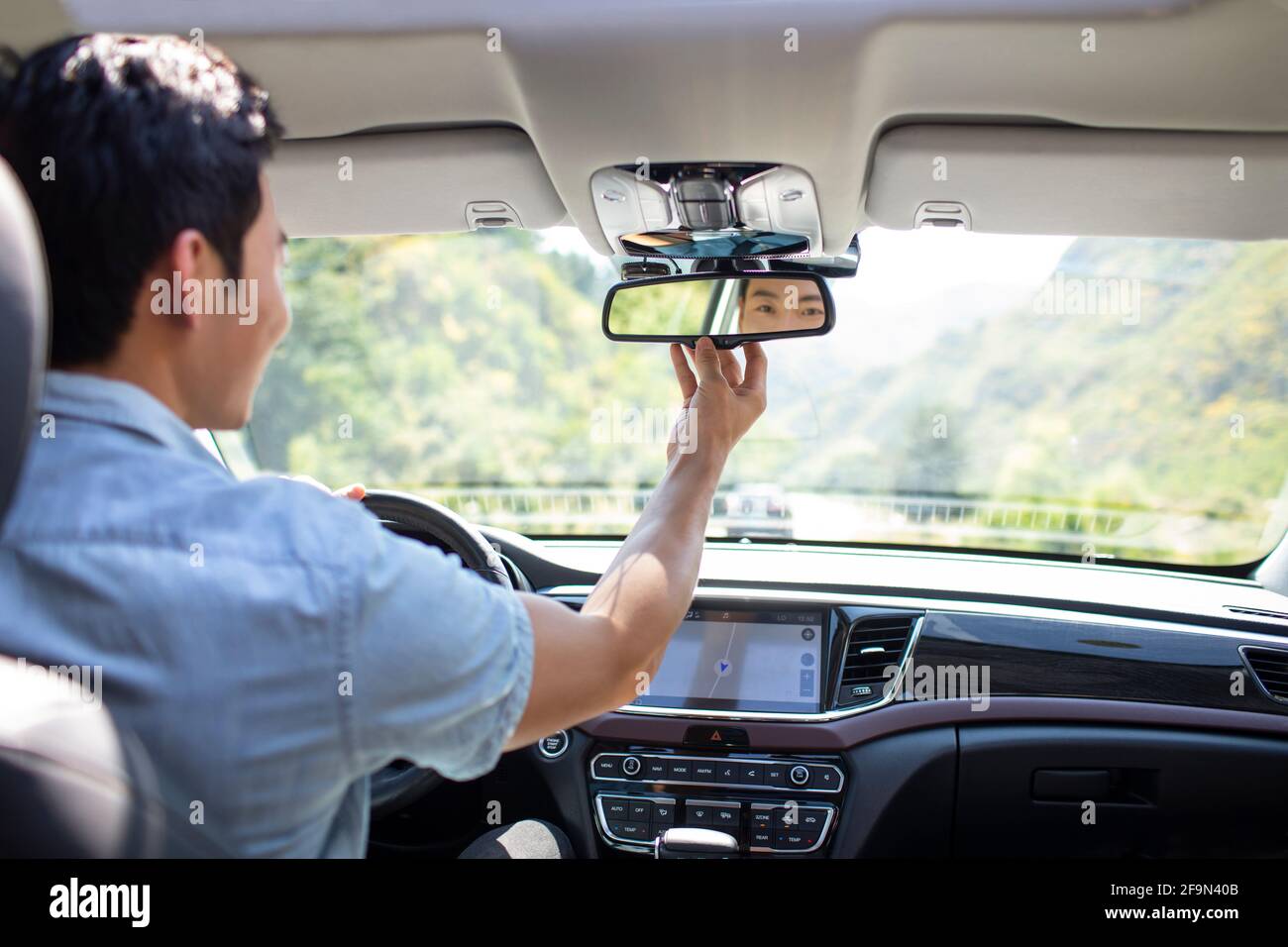 Young man adjusting rear-view mirror in car Stock Photo - Alamy
