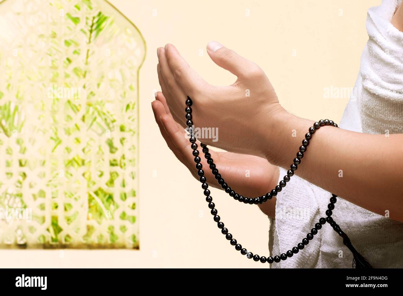 A Muslim man in ihram clothes praying with prayer beads on his hands on ...