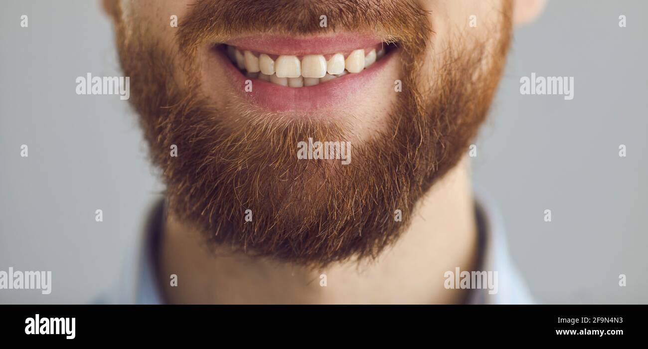 Close up view of toothy white wide male smile on grey studio blank ...