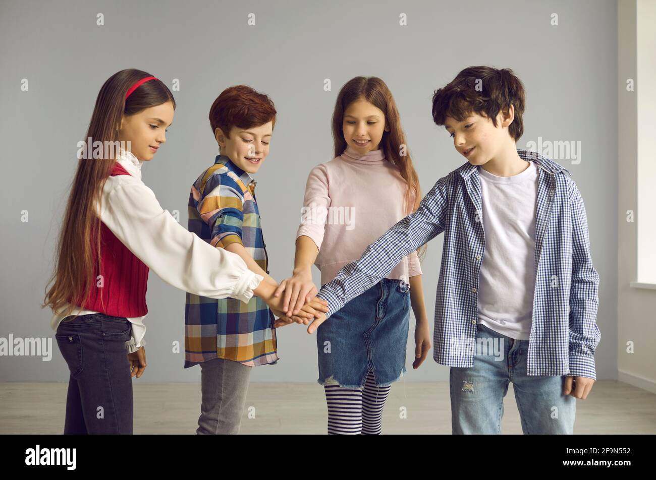 Group of children stand and join hands together studio shot on copy ...