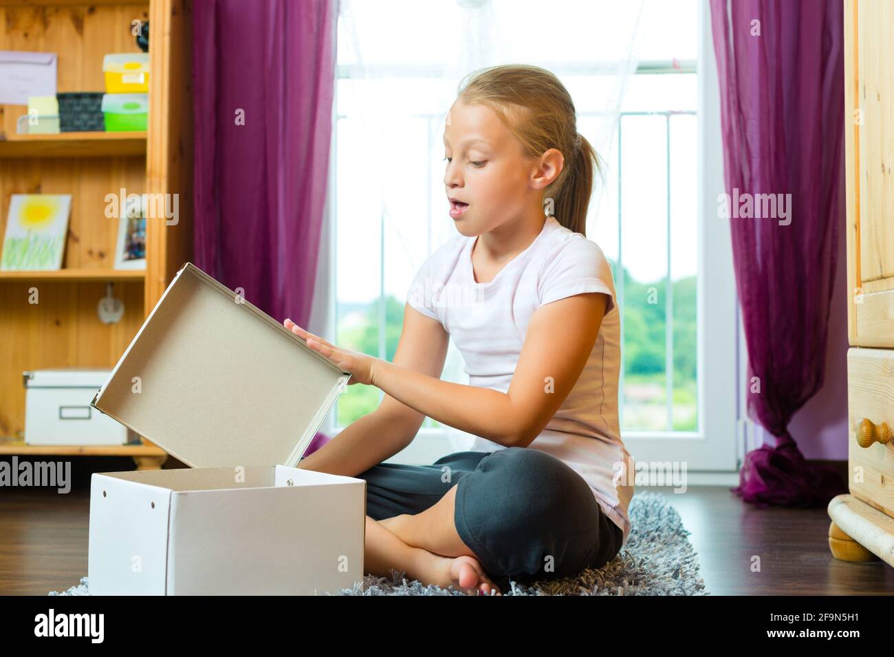 Family - child or teenager open a gift or box at home in the living ...