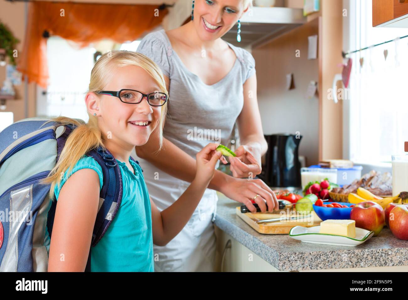 Family - mother making breakfast for her children in the morning and a ...