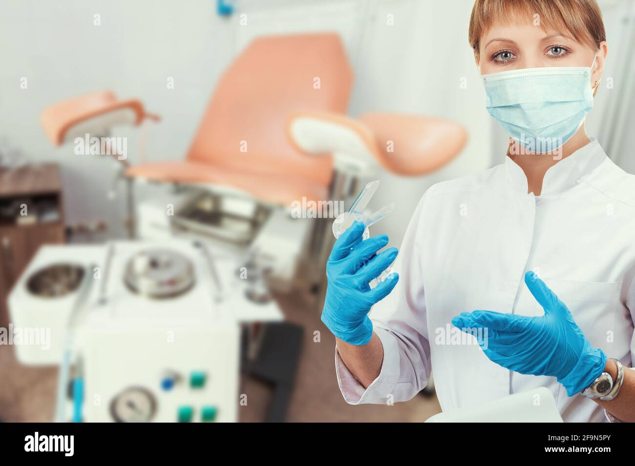 Female gynecologist in protective mask and whitecoat with gynecological ...