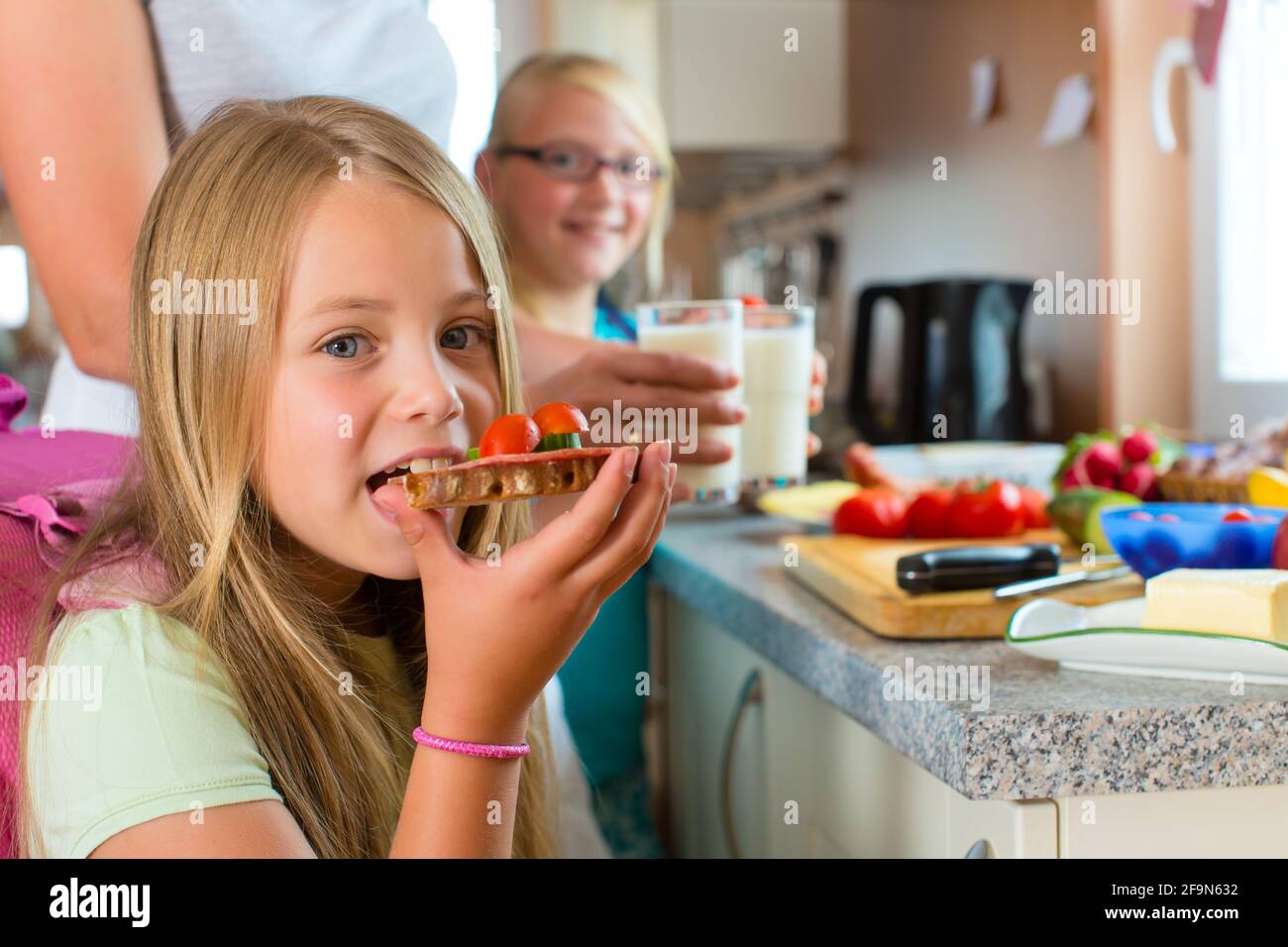 Family - mother making breakfast for her children in the morning and a ...