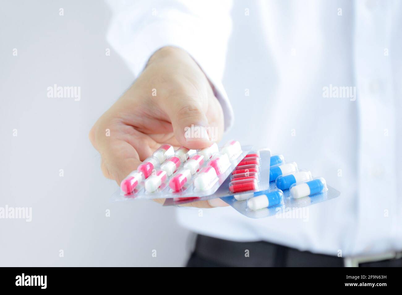 Hand giving medicines - capsules in blister packs Stock Photo - Alamy
