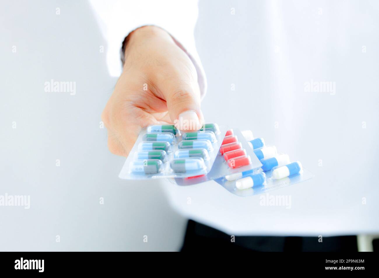 Hand giving medicines - capsules in blister packs Stock Photo - Alamy