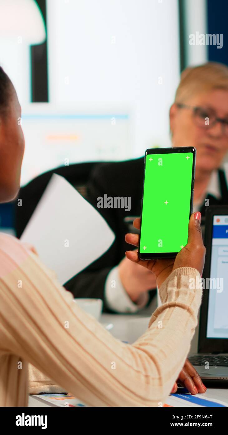 Back view of black businesswoman sitting at conference desk holding ...