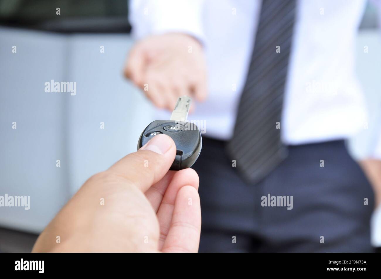 Hand giving a car key to another man - car sale & rental service ...