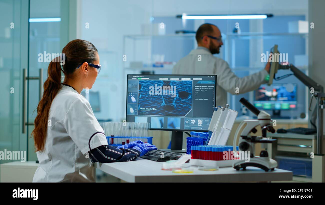 Chemistry doctor analysing blood sample and typing on computer while ...