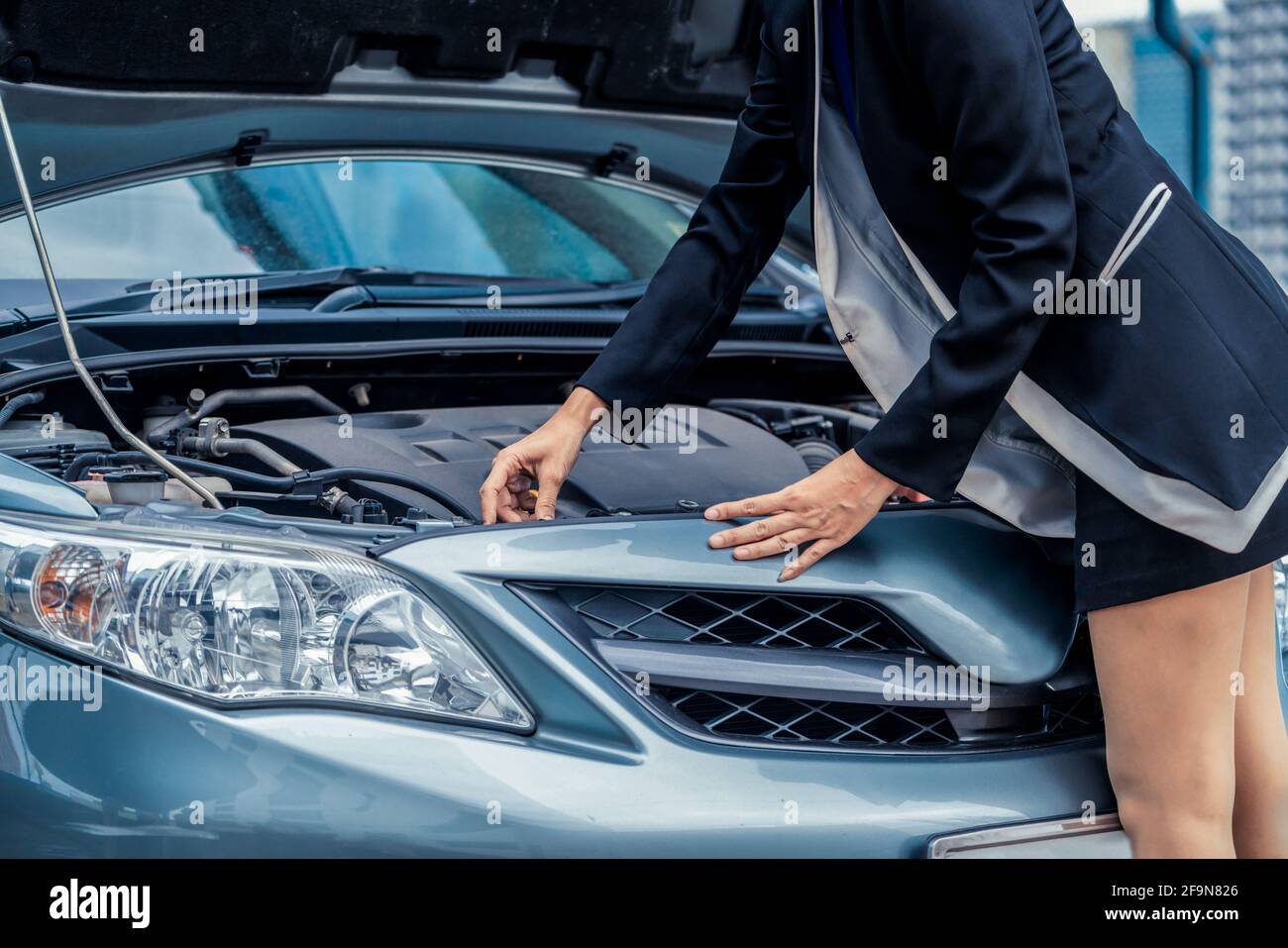 A business woman whose car breakdown try to fix the car by herself ...