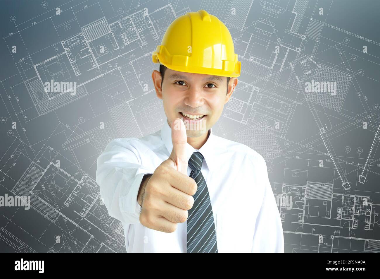 Smiling Asian engineer (or architect ) with yellow hard hat giving ...