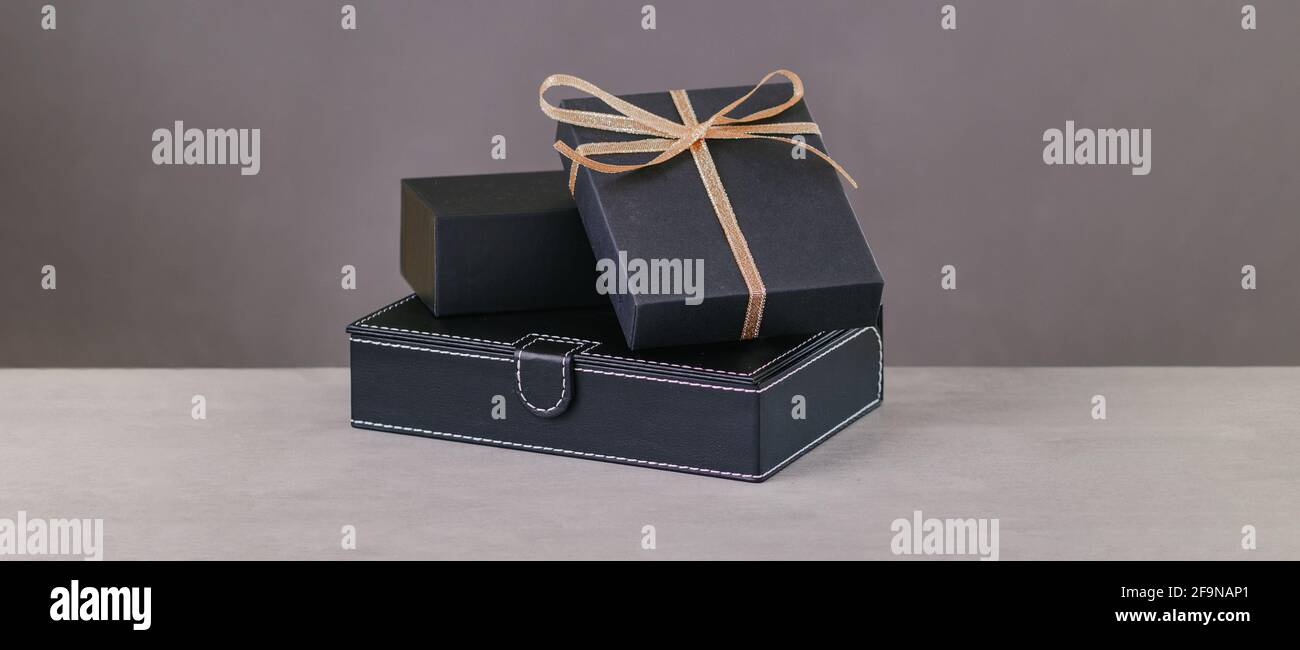 Back gift box. Golden ribbon on gift on a grey background. Copy space ...