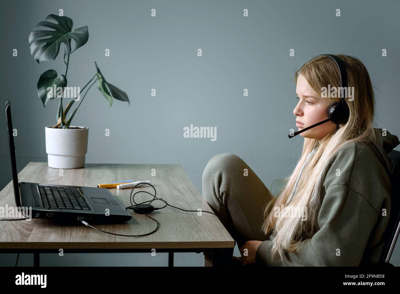 Teenage girl in headphones with microphone studying online at home ...