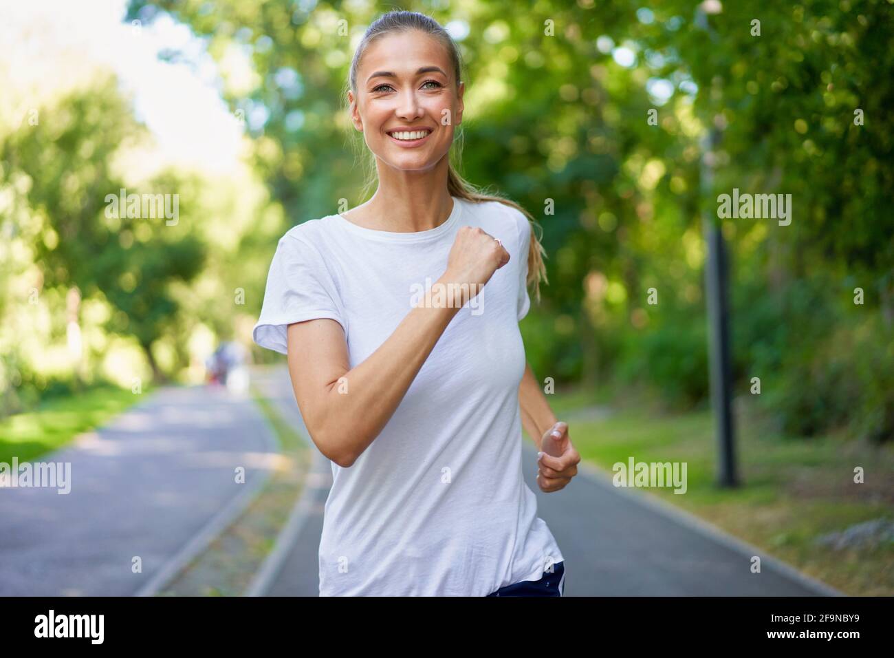Woman running asphalt road summer park Active sporty caucasian female ...