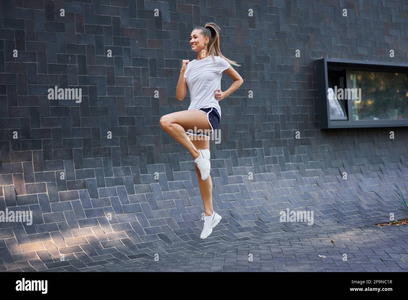 Woman jumping and running against black wall background. Female model ...