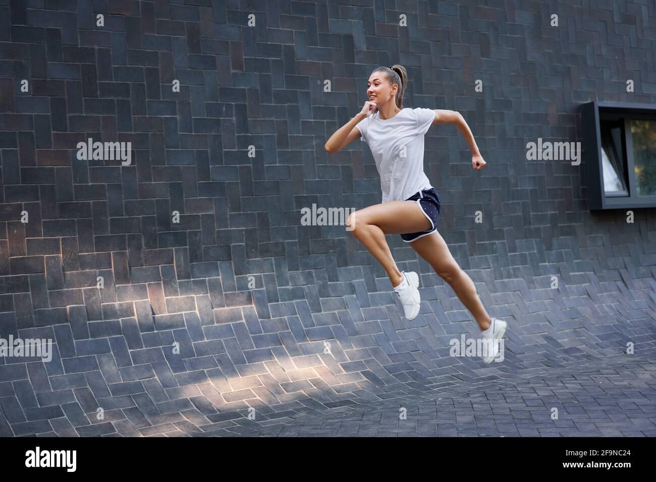 Woman jumping and running against black wall background. Female model ...