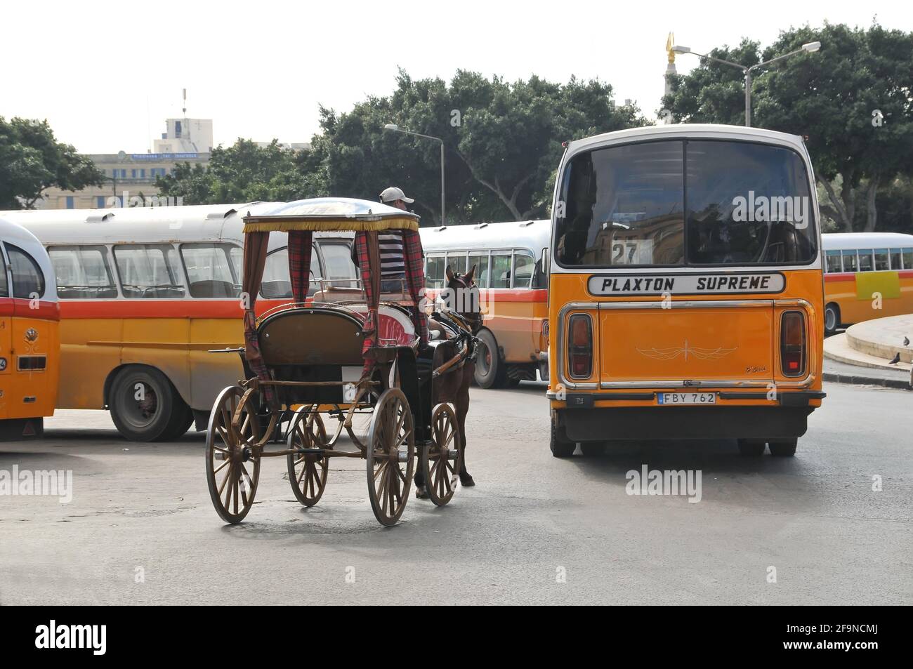 Traditional yellow buses, city transport and tourist cart with horse on ...
