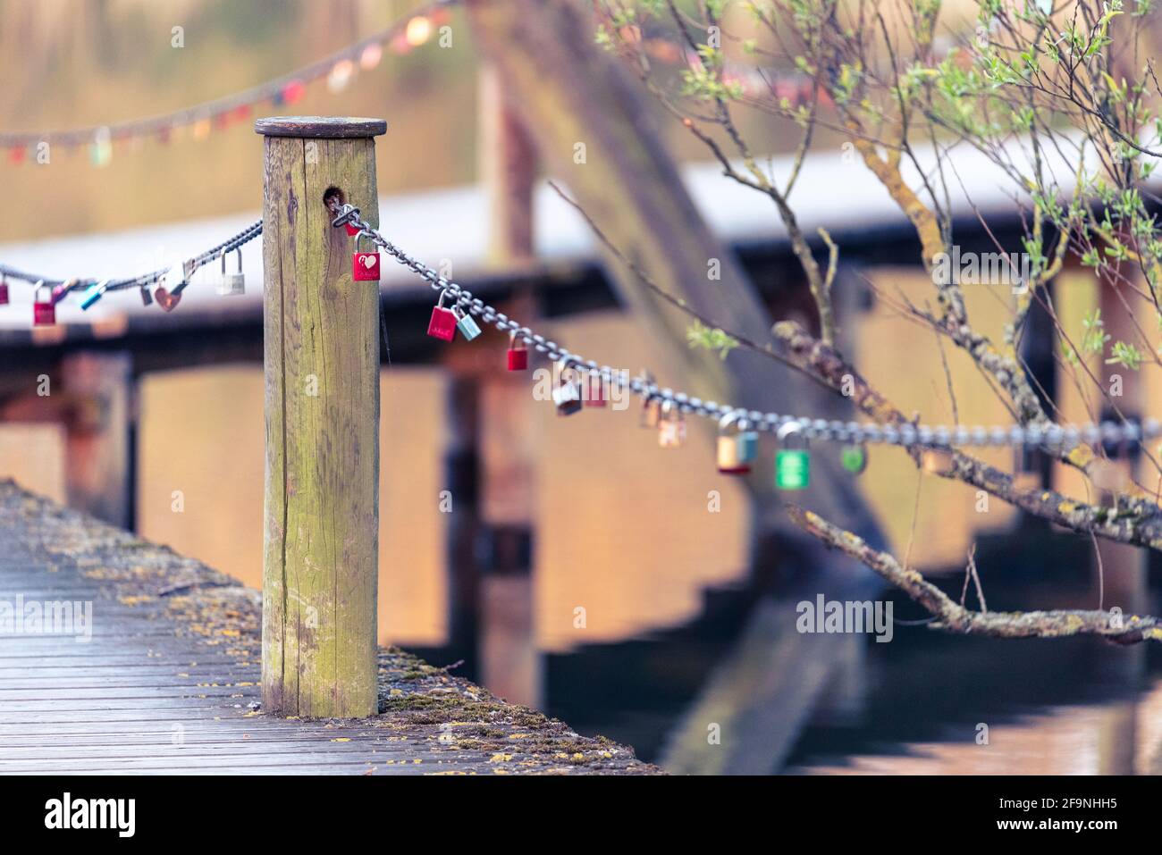 Wooden pedestrian bridge with piers and chain with love locks hanging ...