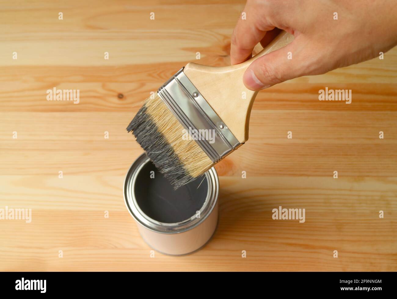 Man's hand holding paintbrush dipping paint on the wood plank Stock ...