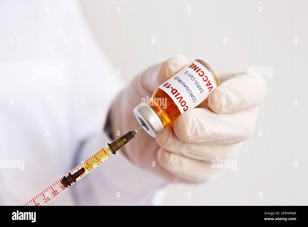 Macro shot of doctor's hands in latex gloves filling the syringe with ...