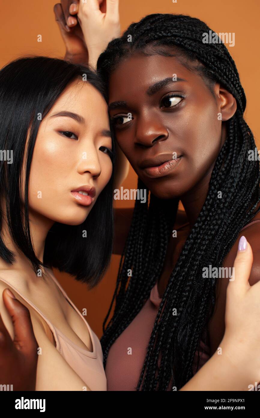 young pretty asian, afro woman posing cheerful together on brown ...
