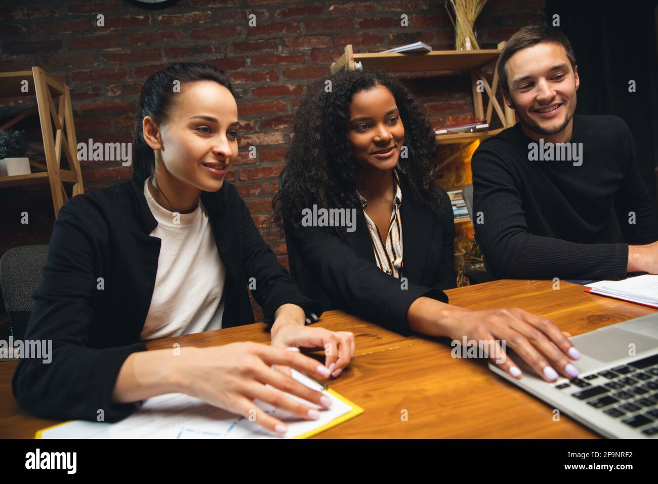 Colleagues working together in modern office using devices and gadgets ...