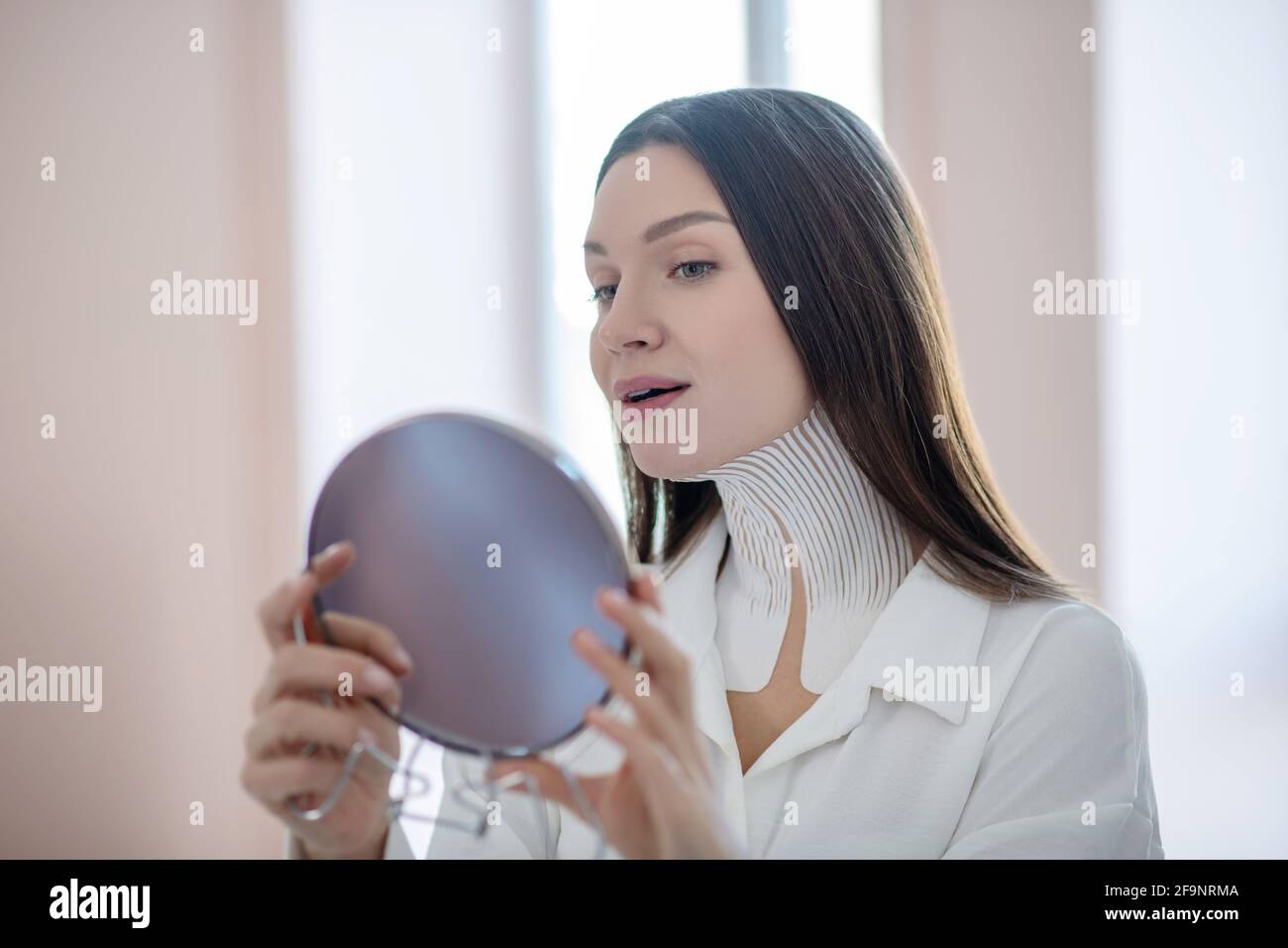 Cute young woman with tapes on her neck looking in the mirror Stock ...